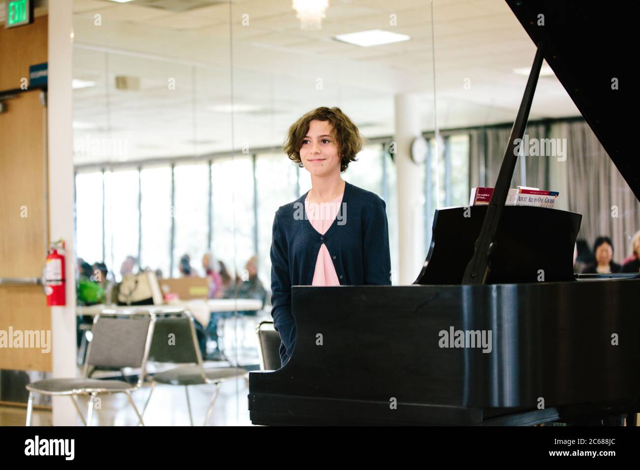 Teen girl smiles and stands by a grand piano after her recital Stock ...