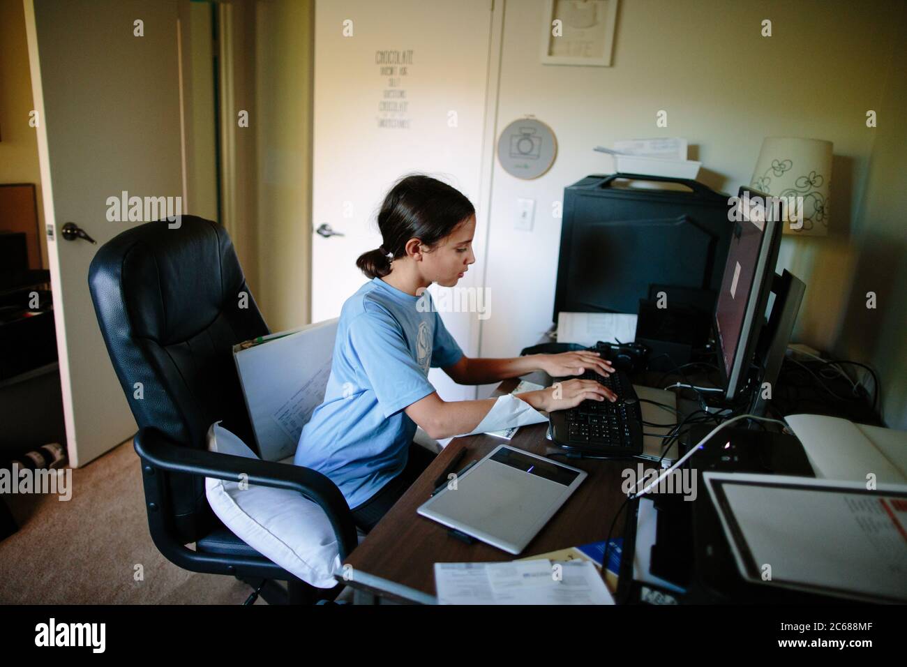 Tween girl sits at a desktop computer typing Stock Photo - Alamy
