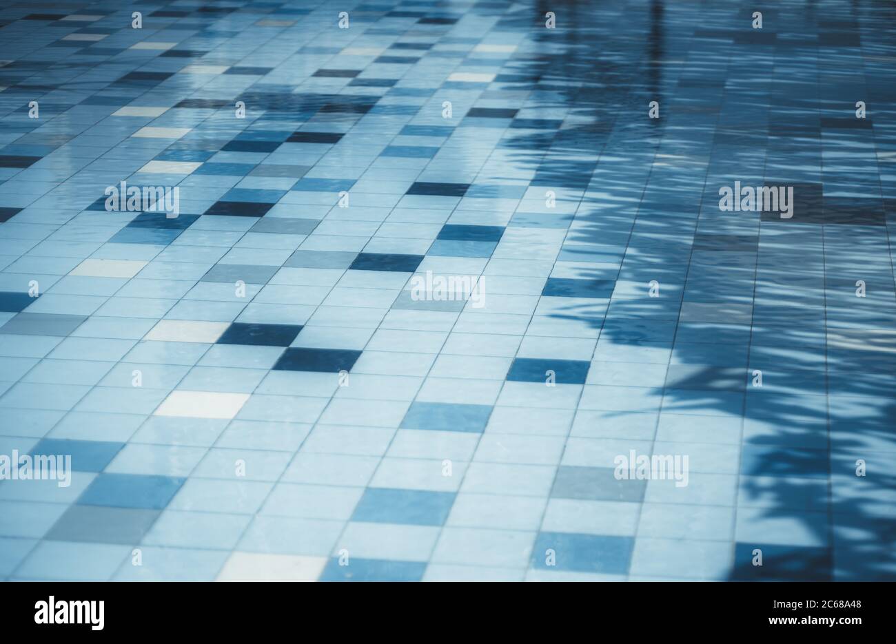 A tiled bottom surface of a street pool with water of classic blue ...