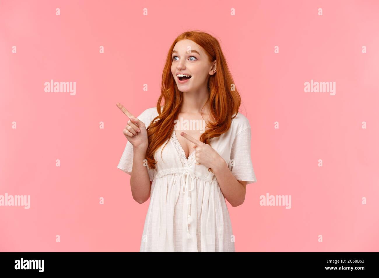 Curious and amused caucasian foxy girl in white dress, pointing fingers ...