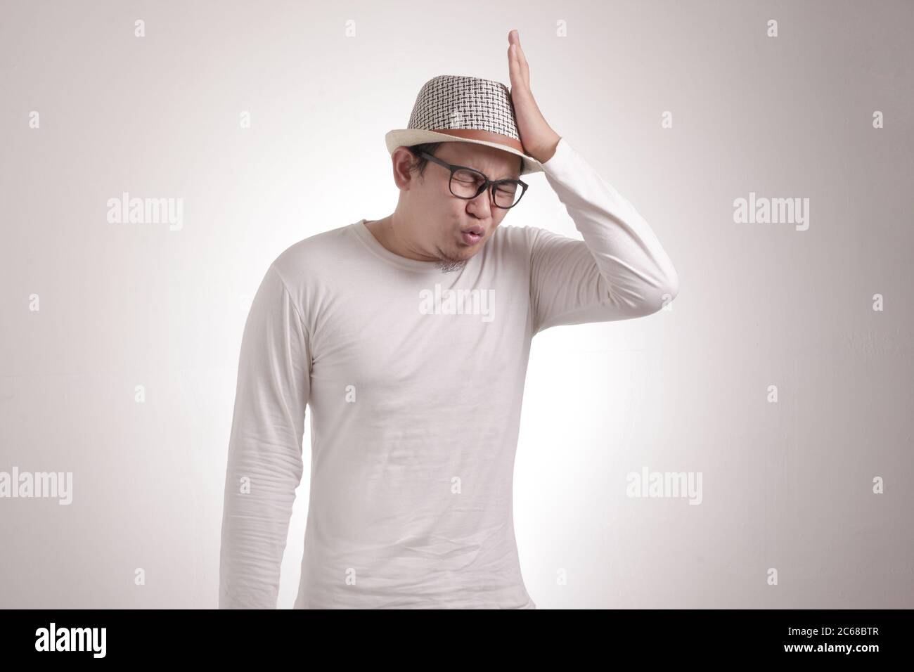 Asian man shows regret gesture, hits his forehead, agains white ...