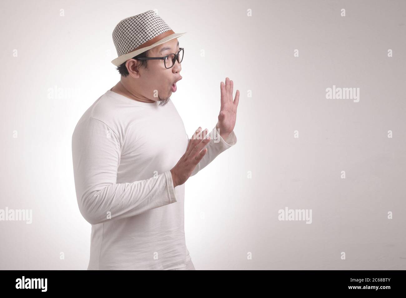 Portrait of young Asian man shocked to see something on his side ...