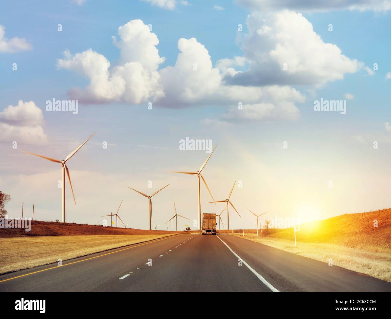Traffic moves along an interstate highway with wind turbines at sunset ...