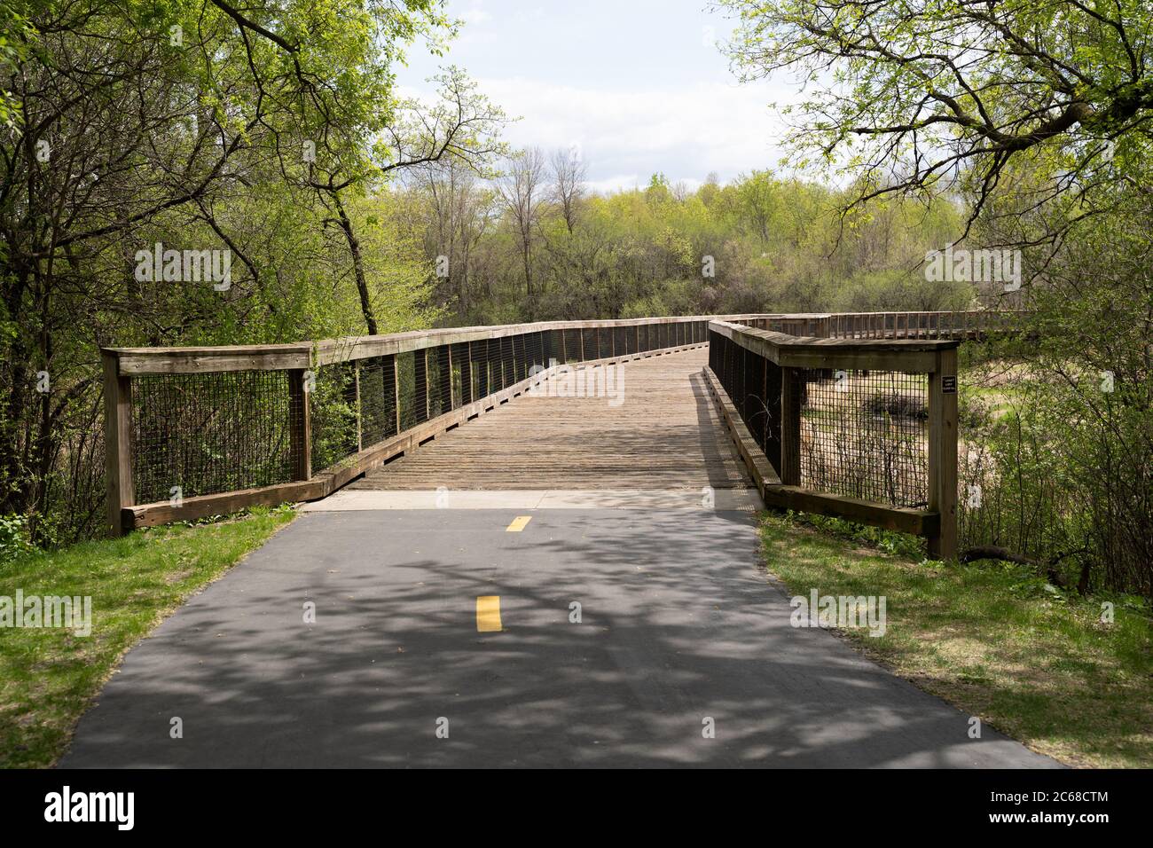 Pedestrian bridge over a creek and marsh wetland in Elm Creek Park ...