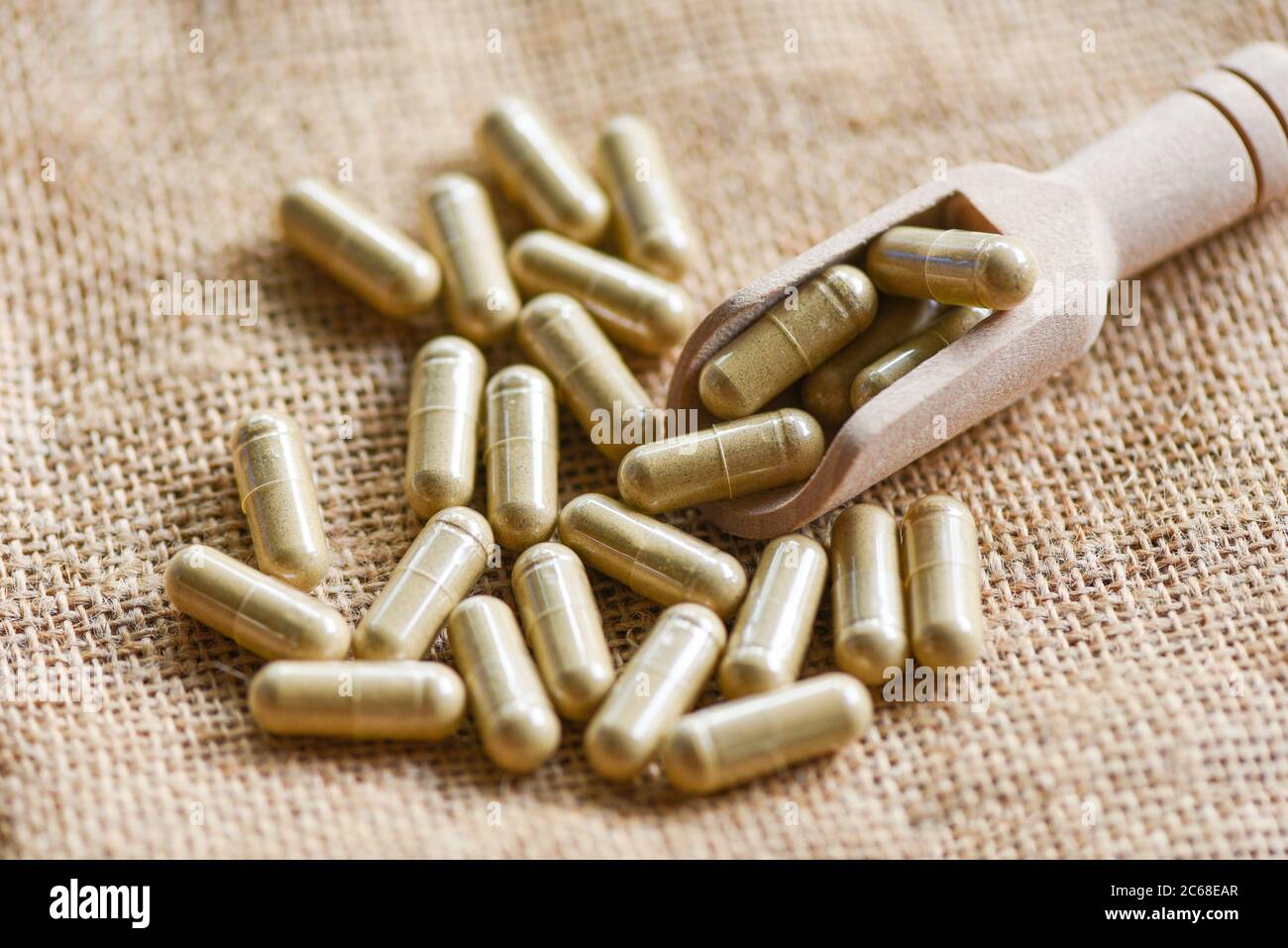Pile of herbal capsules on wooden scoop from herbs on sack background ...