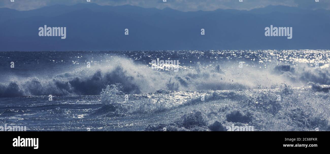 Man standing against the sea on a pier with big wave beating with ...