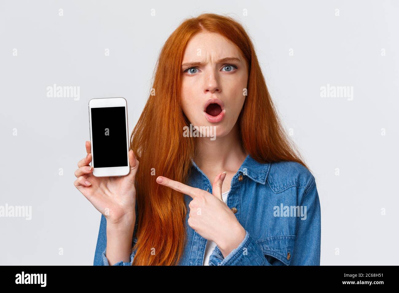 Close-up portrait angry and pissed-off redhead girl showing photos from ...