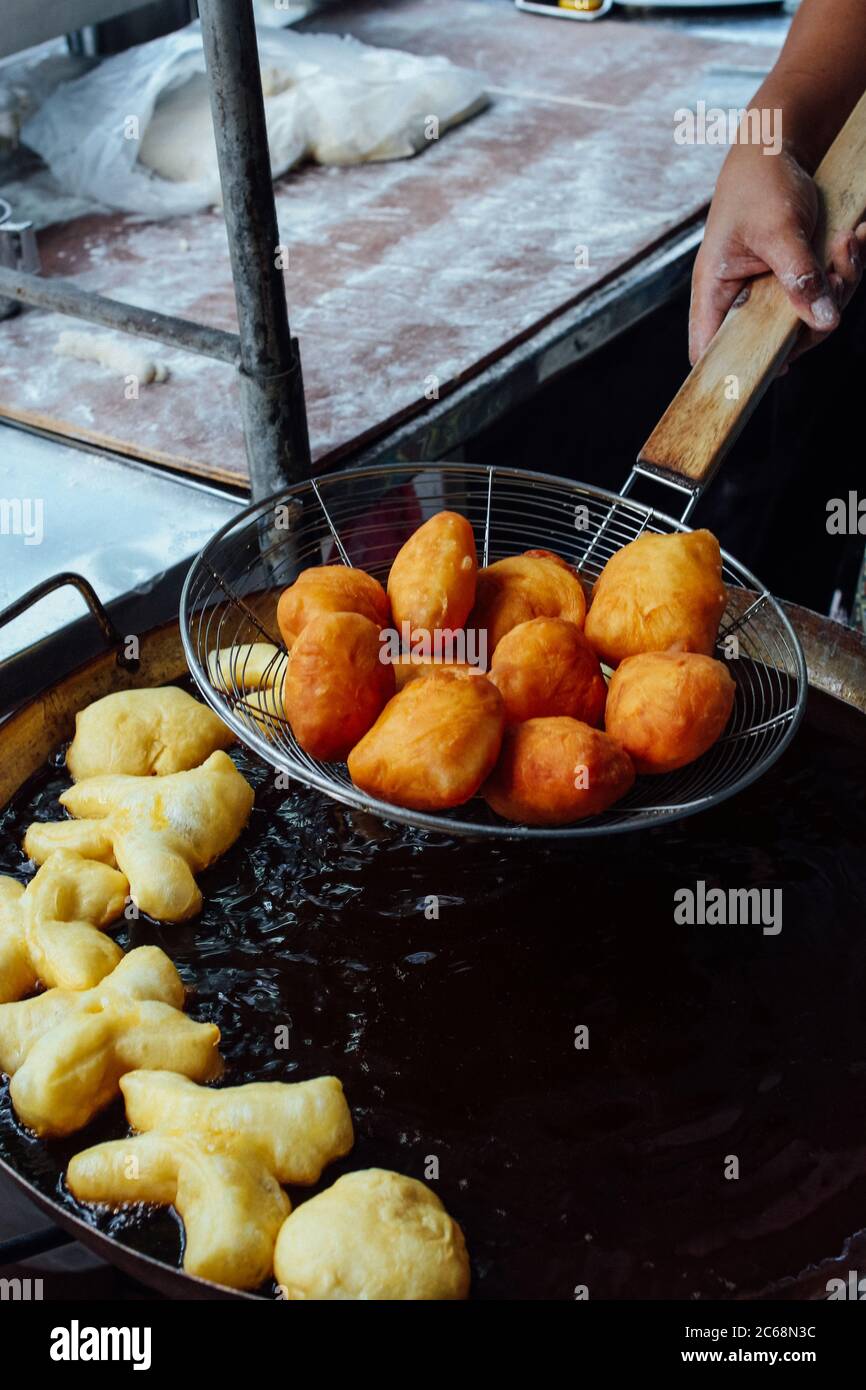 Finished fried chinese bread sticks rest on a colander to drain the oil ...