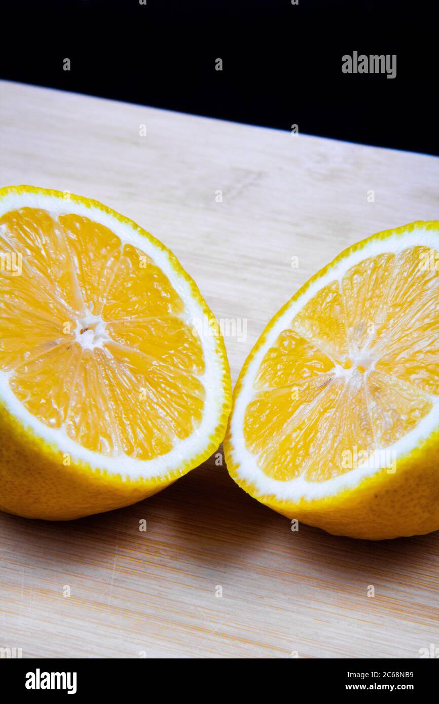 Lemon halved on a wooden board with a black background Stock Photo - Alamy