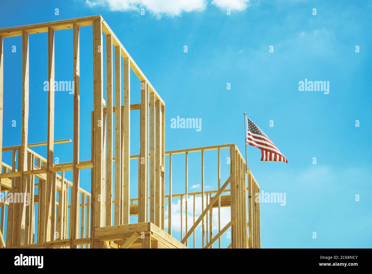 American flag waving in the wind on the top of a construction home ...