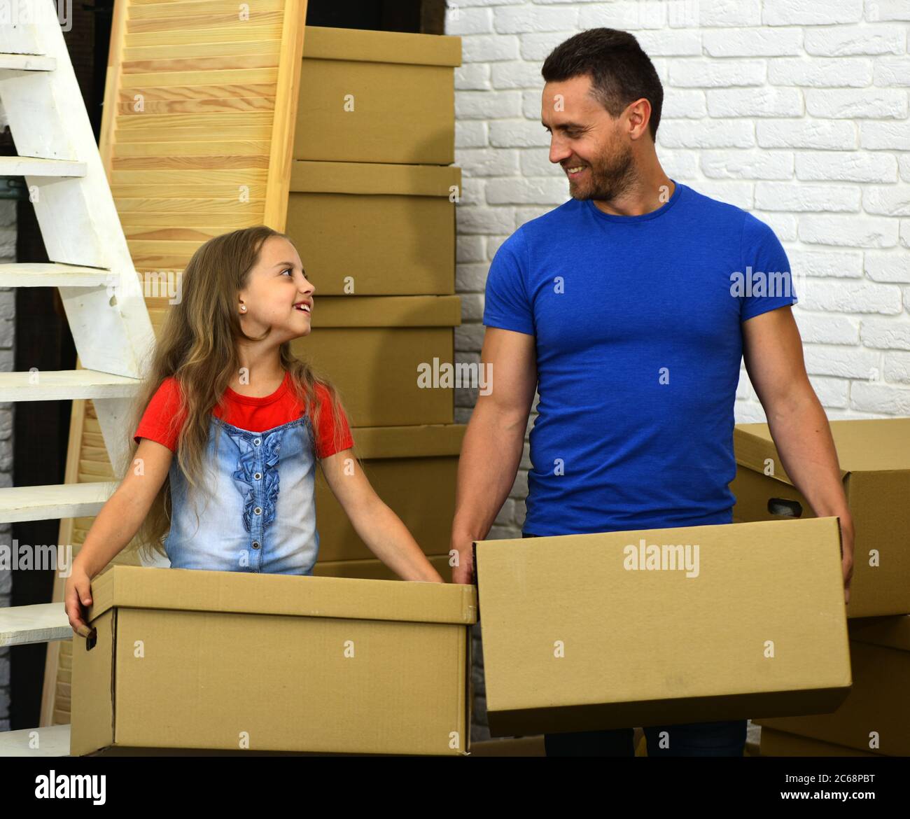 Dad and daughter stand by pile of cardboard boxes. Deliveryman and ...