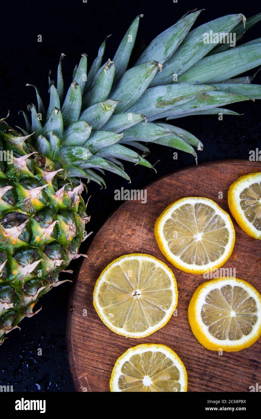 Thin cross sections of a fresh ripe lemon near a big pineapple Stock ...