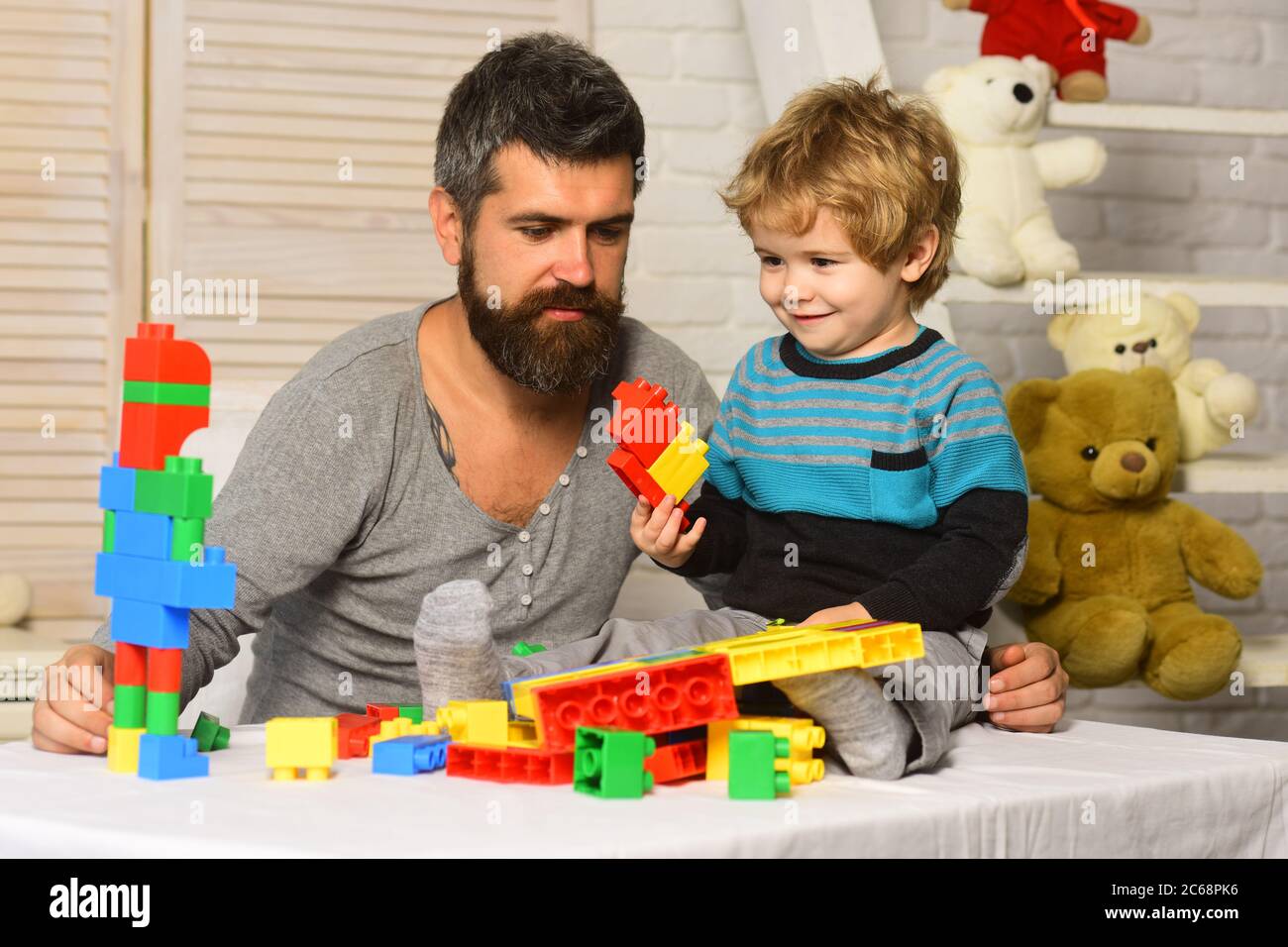 Dad and kid with toys on background build of plastic blocks. Father and ...