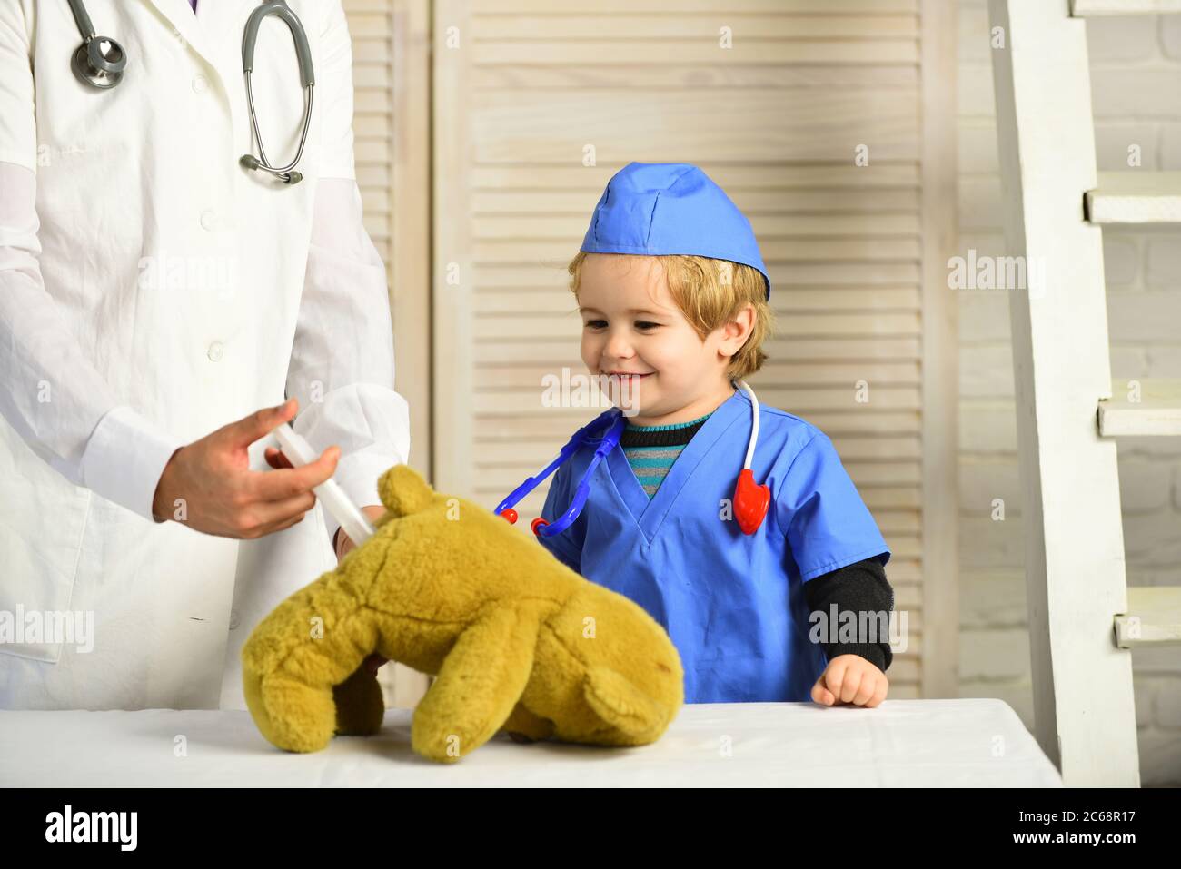 Little assistant makes injection to teddy bears. Male in surgical coat ...