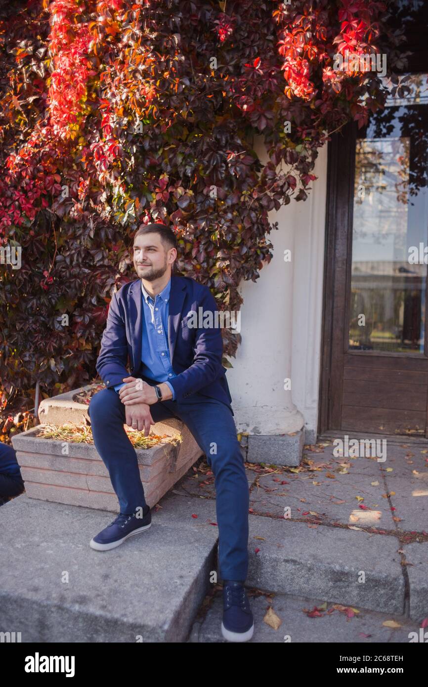 a man in suit sits near the classic building Stock Photo - Alamy