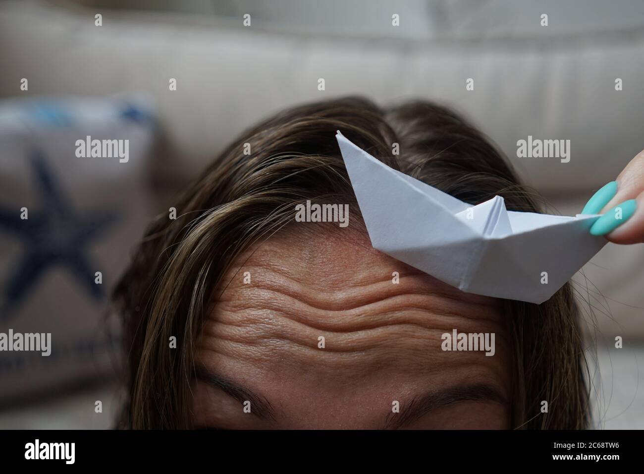 Forehead wrinkles as sea close-up. Paper boat in hand with turquoise ...