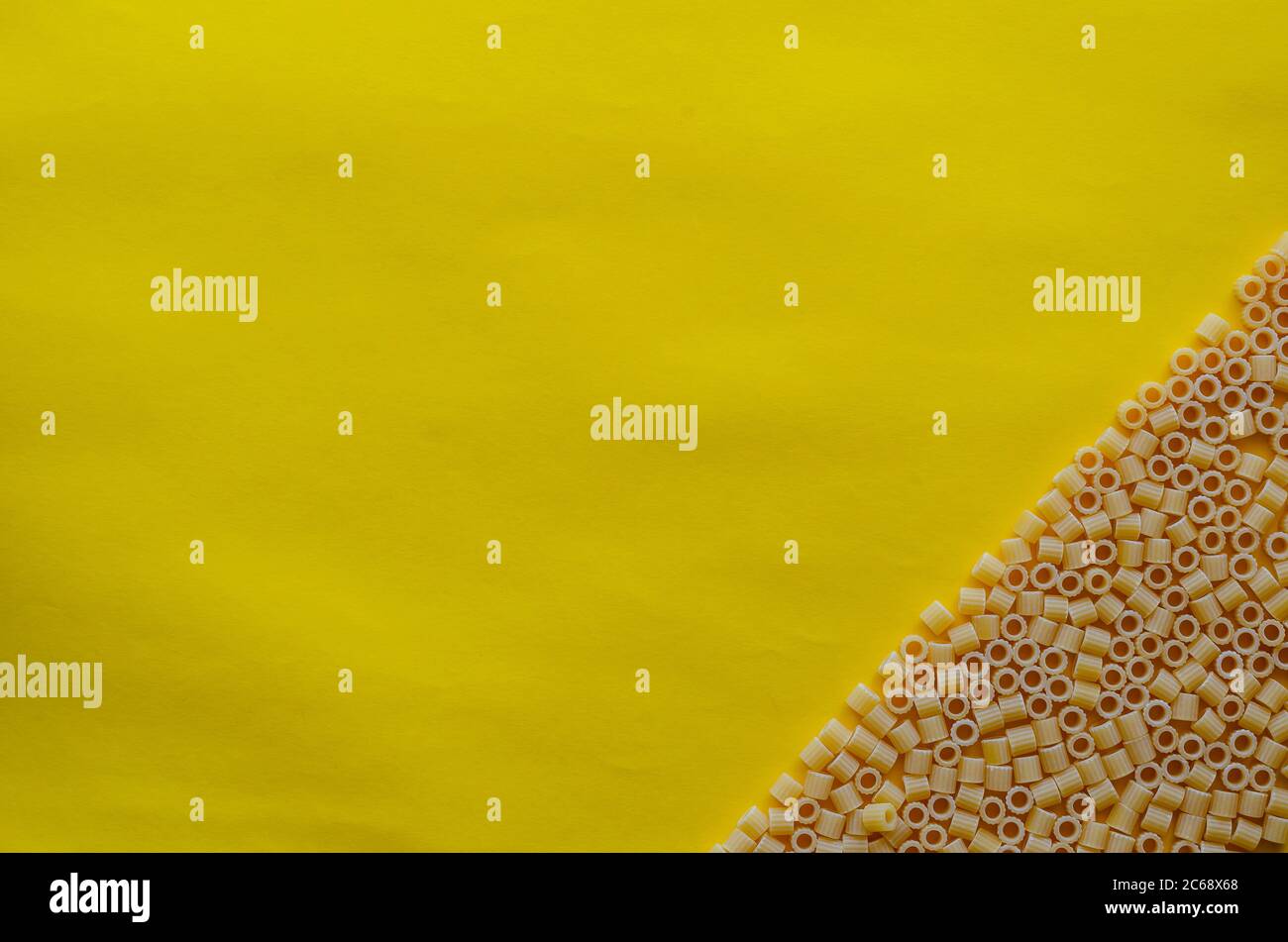 Serving of dried Ditalini pasta in the corner on a yellow background ...