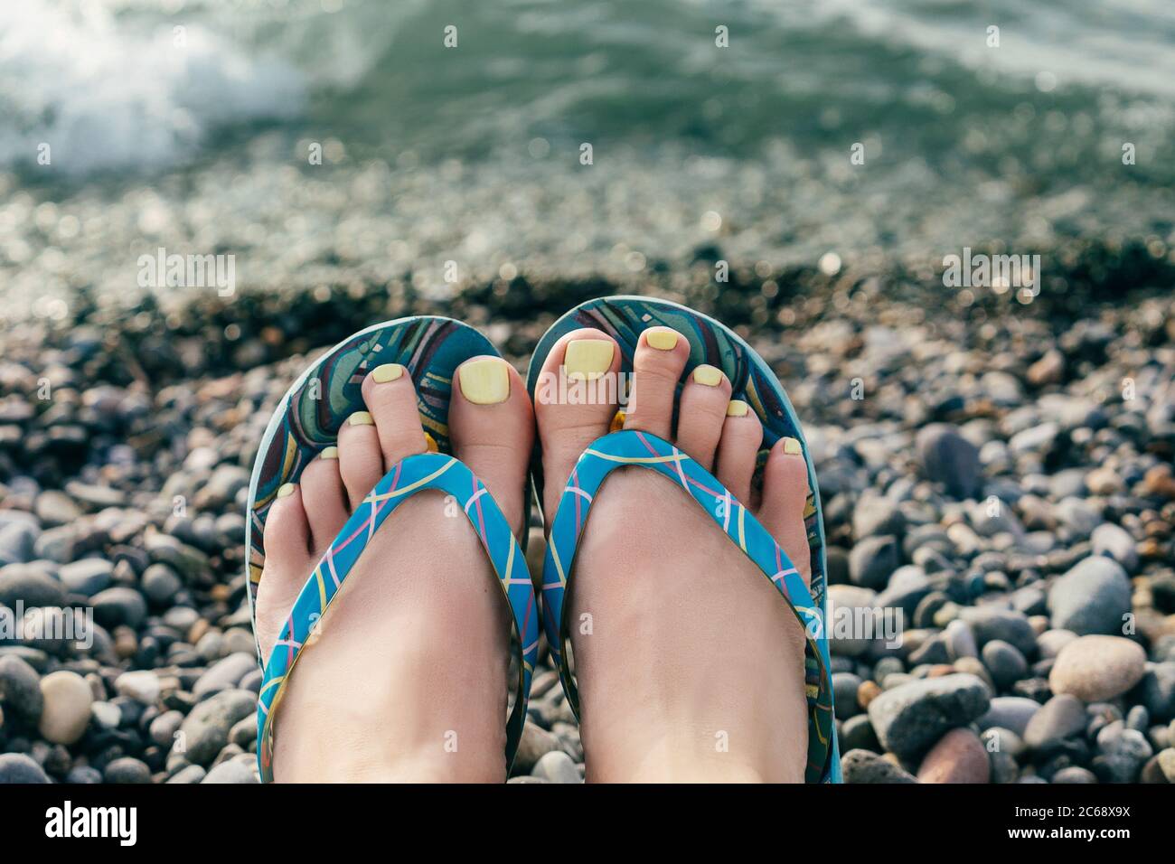 Female legs in blue flip flops shoes with perfect yellow pedicure on ...