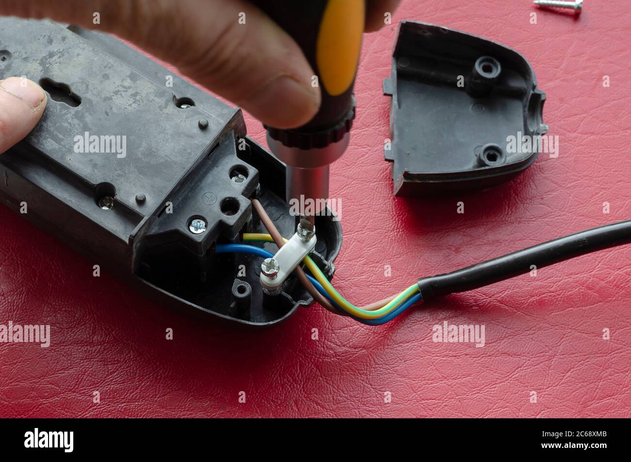 Electrician assembles the electrical splitter with a screwdriver ...