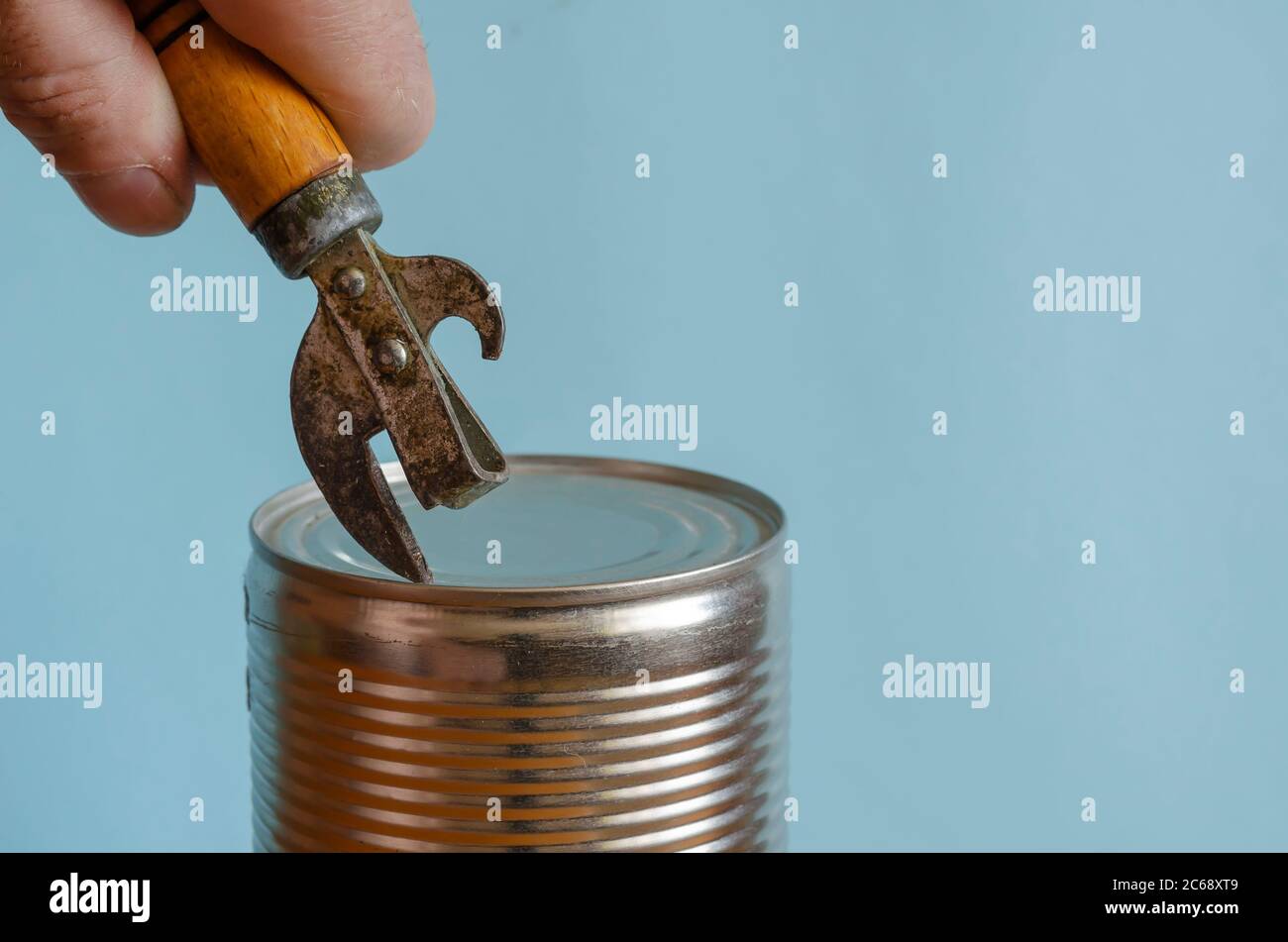 Mans Hands Open A Tin Can With An Old Can Opener With A Wooden Handle
