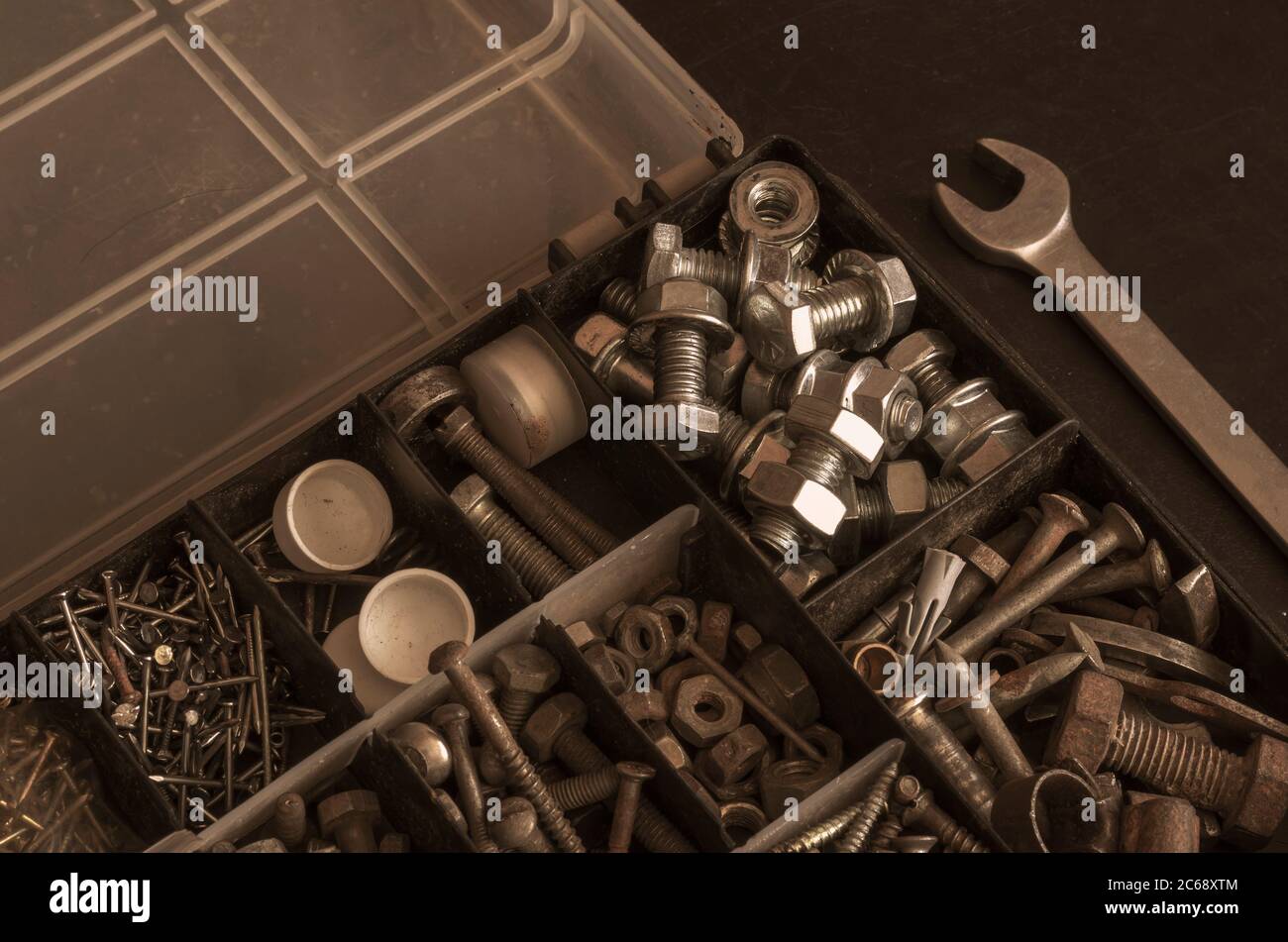 Plastic box with a variety of metal fasteners. Old and new bolts, nuts ...