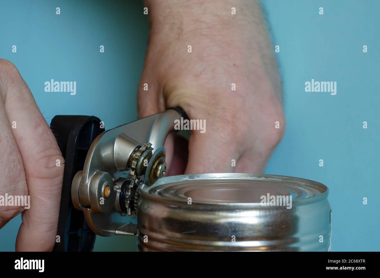 Hands of a man opens a tin can with a can key. Closeup of the process ...