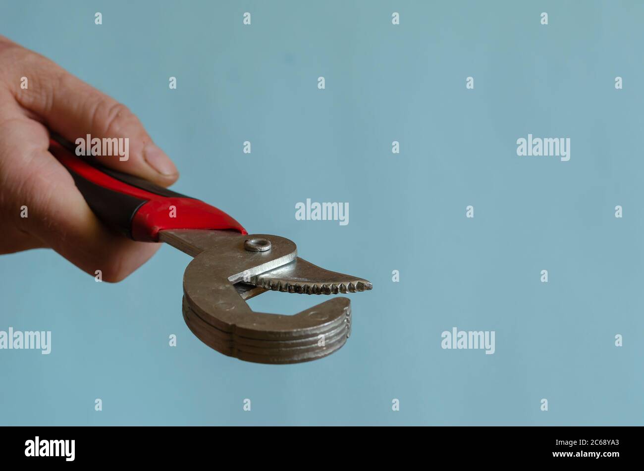 Universal wrench in a male hand. A man's hand shows a tool with a black ...