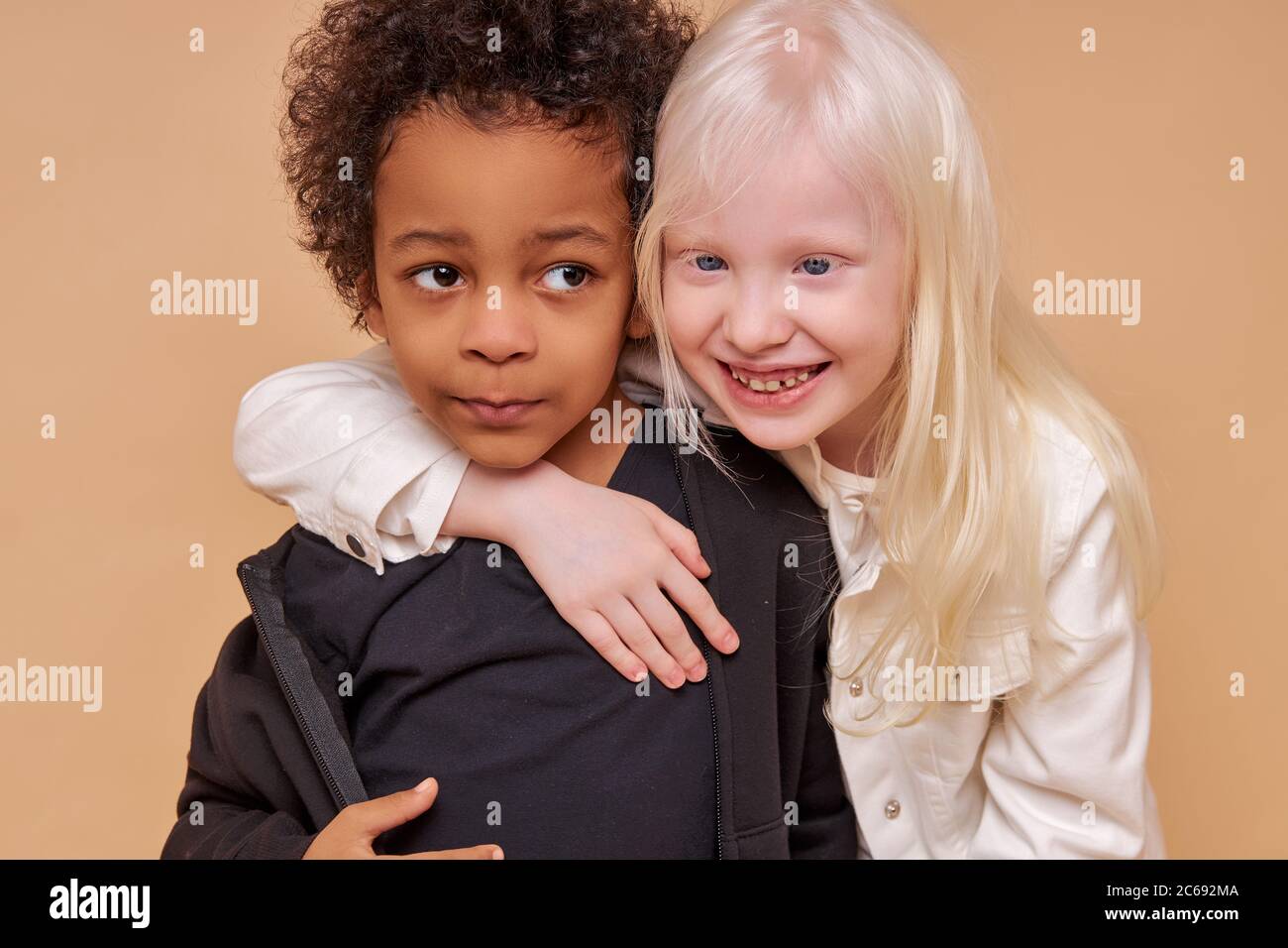 two friendly multiracial children stand together isolated over beige ...