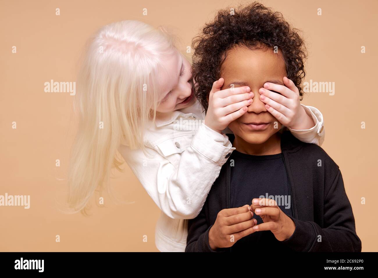 portrait of dark-skinned boy and albino girl playing hide and seek ...