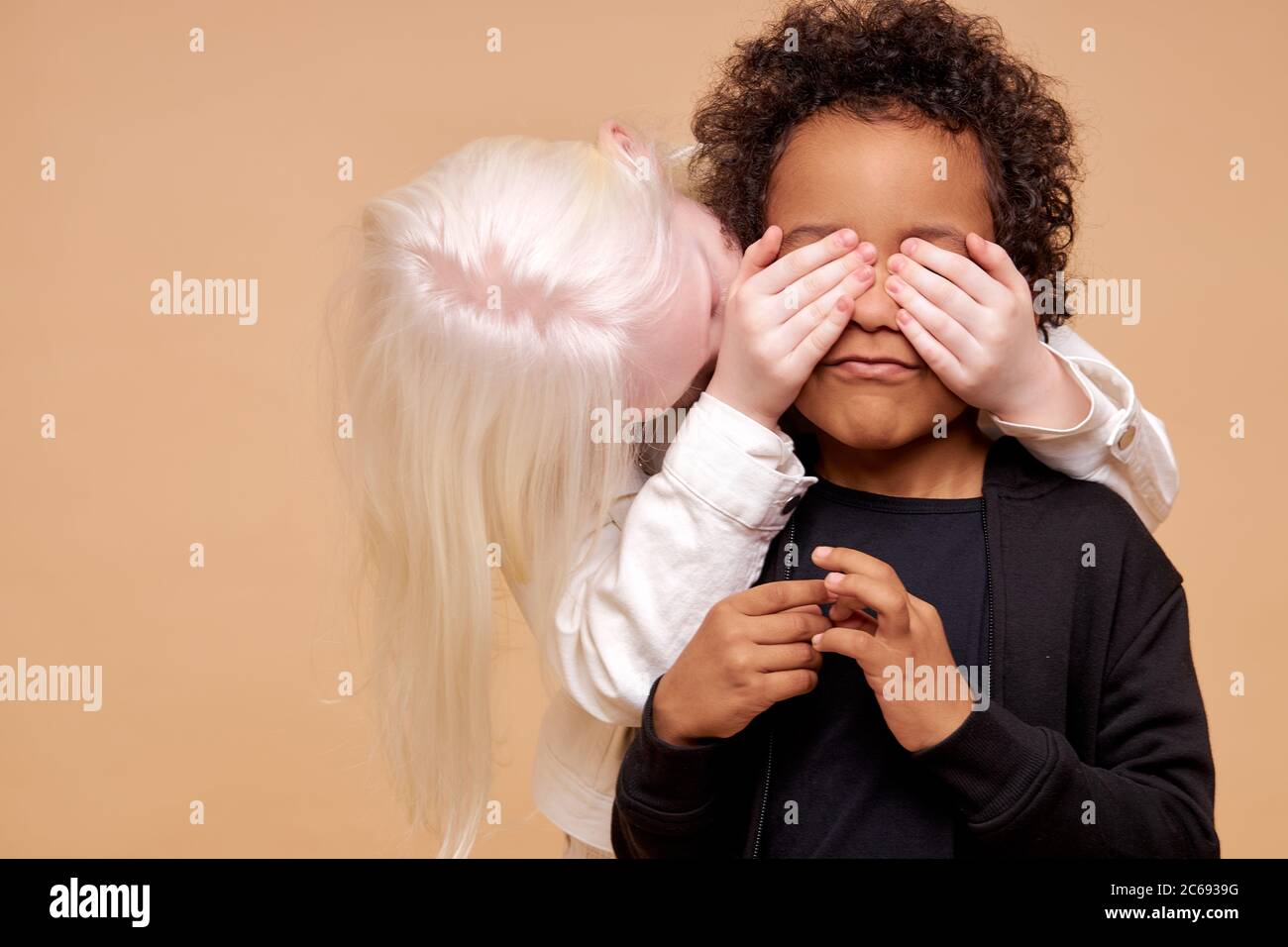 portrait of dark-skinned boy and albino girl playing hide and seek ...