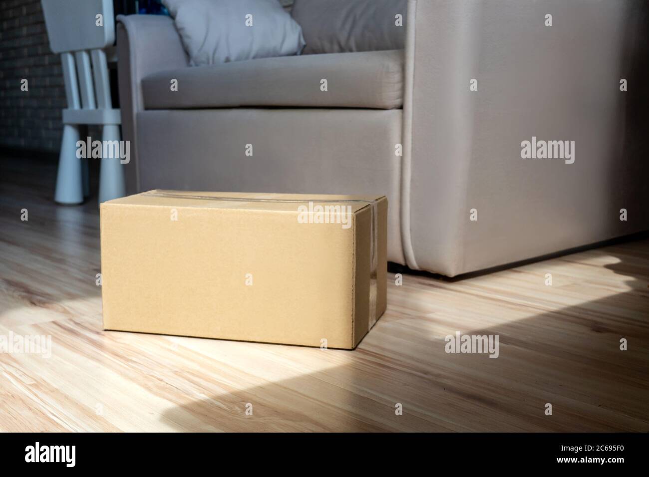 Delivery box closed in sunshine on floor. Home interior Stock Photo - Alamy