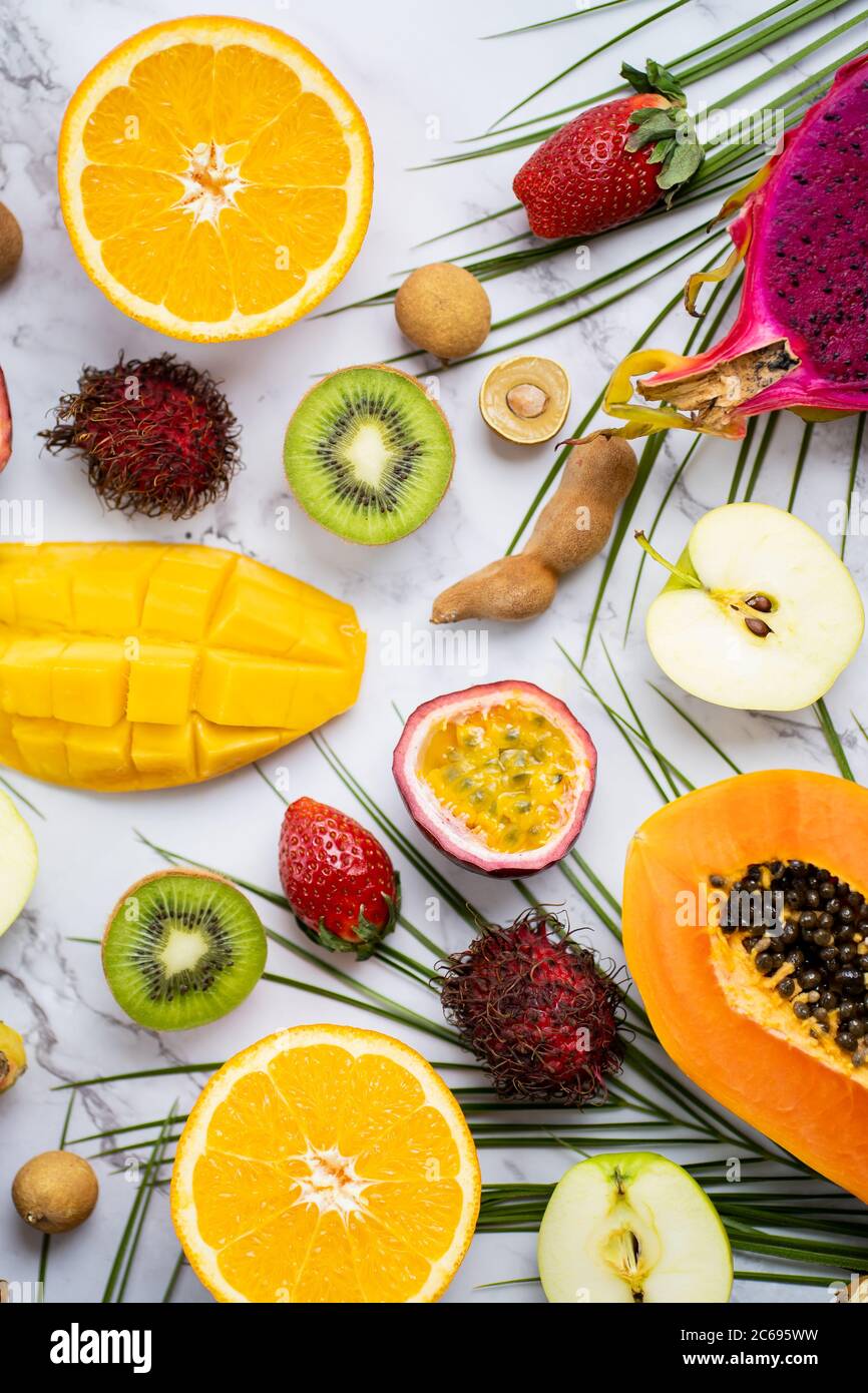Assortment of different exotic fruits with tropical leaves on white ...