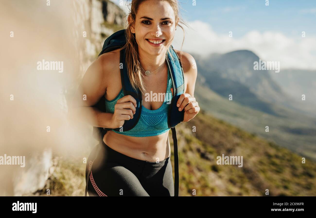 Woman holding her backpack while hiking up a mountain. Female ...
