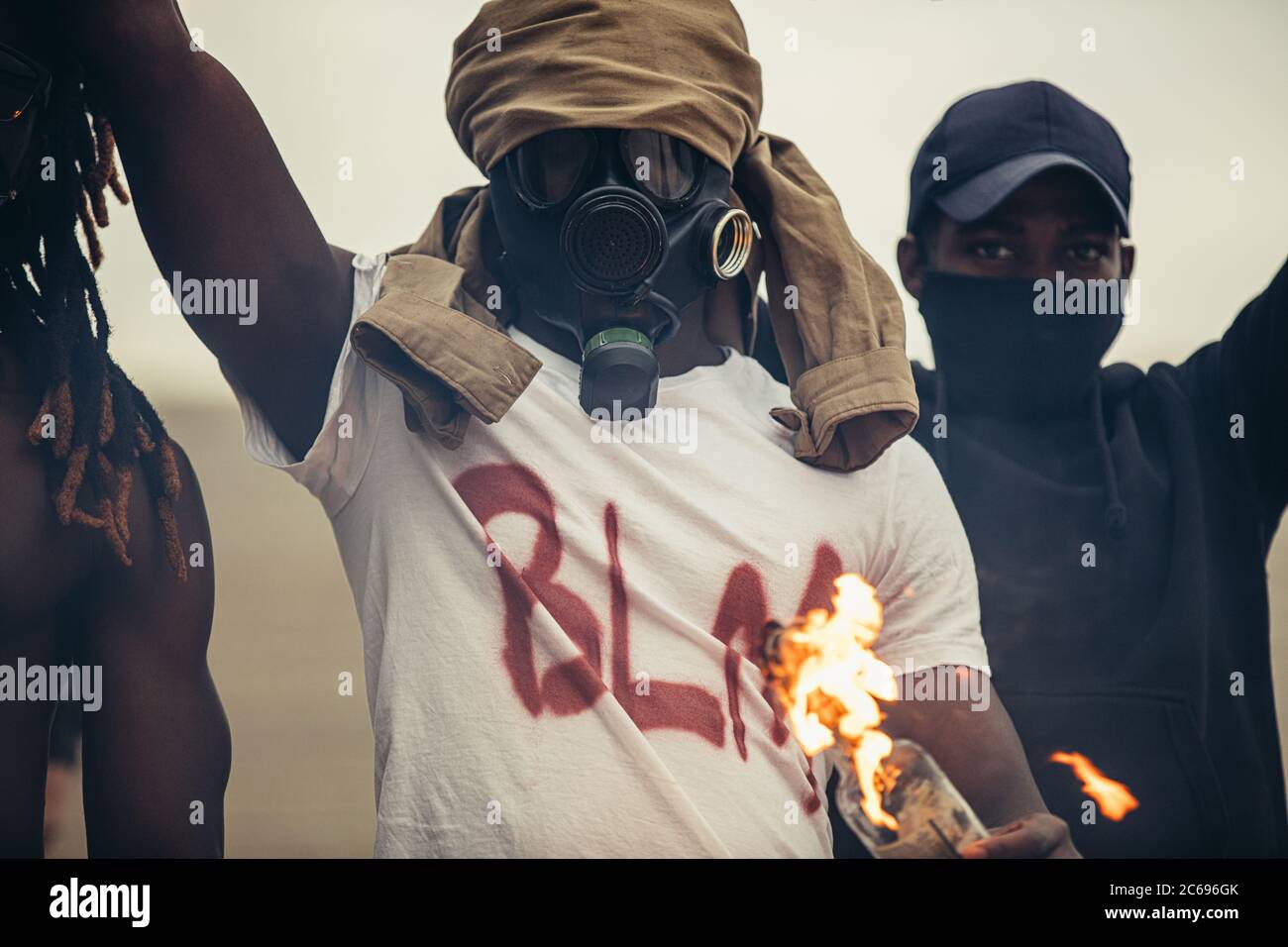 angry group of black people in gas mask riot, set fire to bottles with ...
