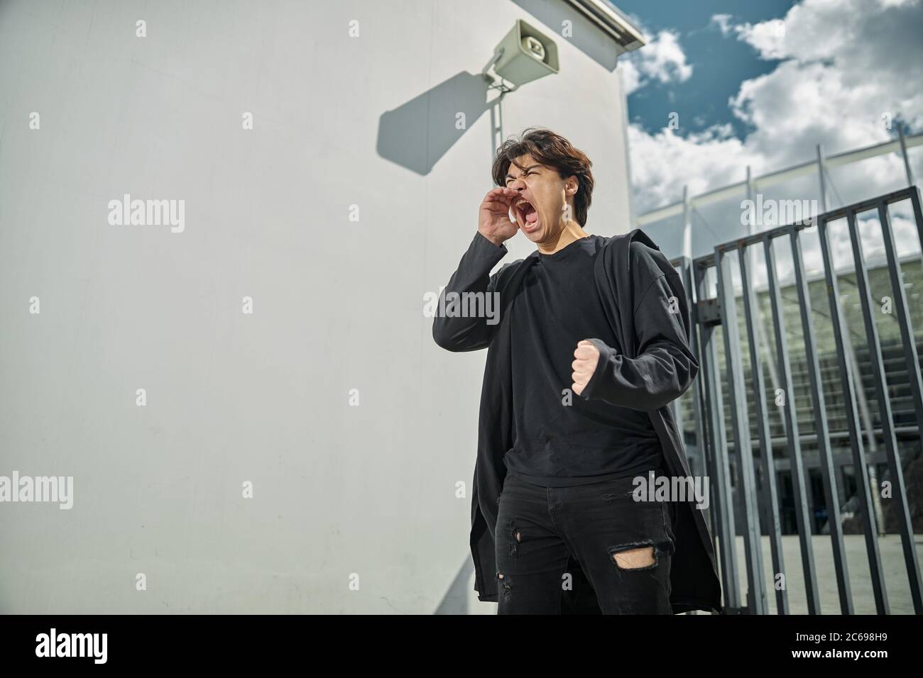 Furious guy in black outfit screaming outdoors Stock Photo - Alamy