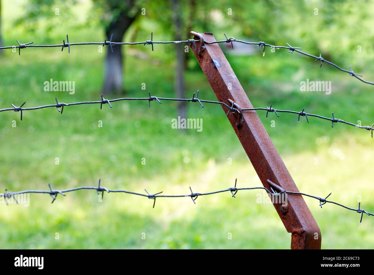 The barbed wire is stretched on a rusty iron support against the ...