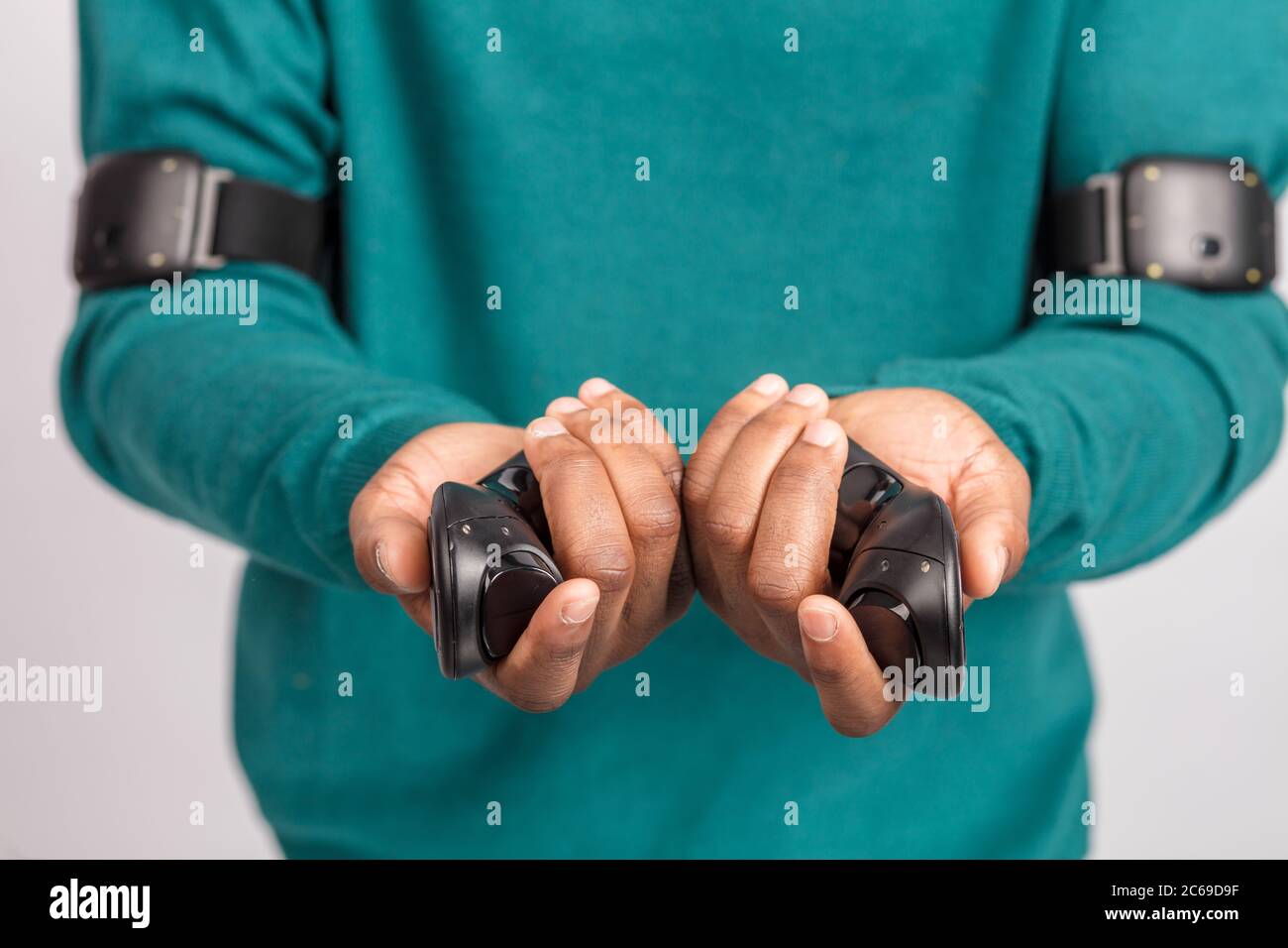 Hands holding controllers from virtual reality headset. Grey background ...