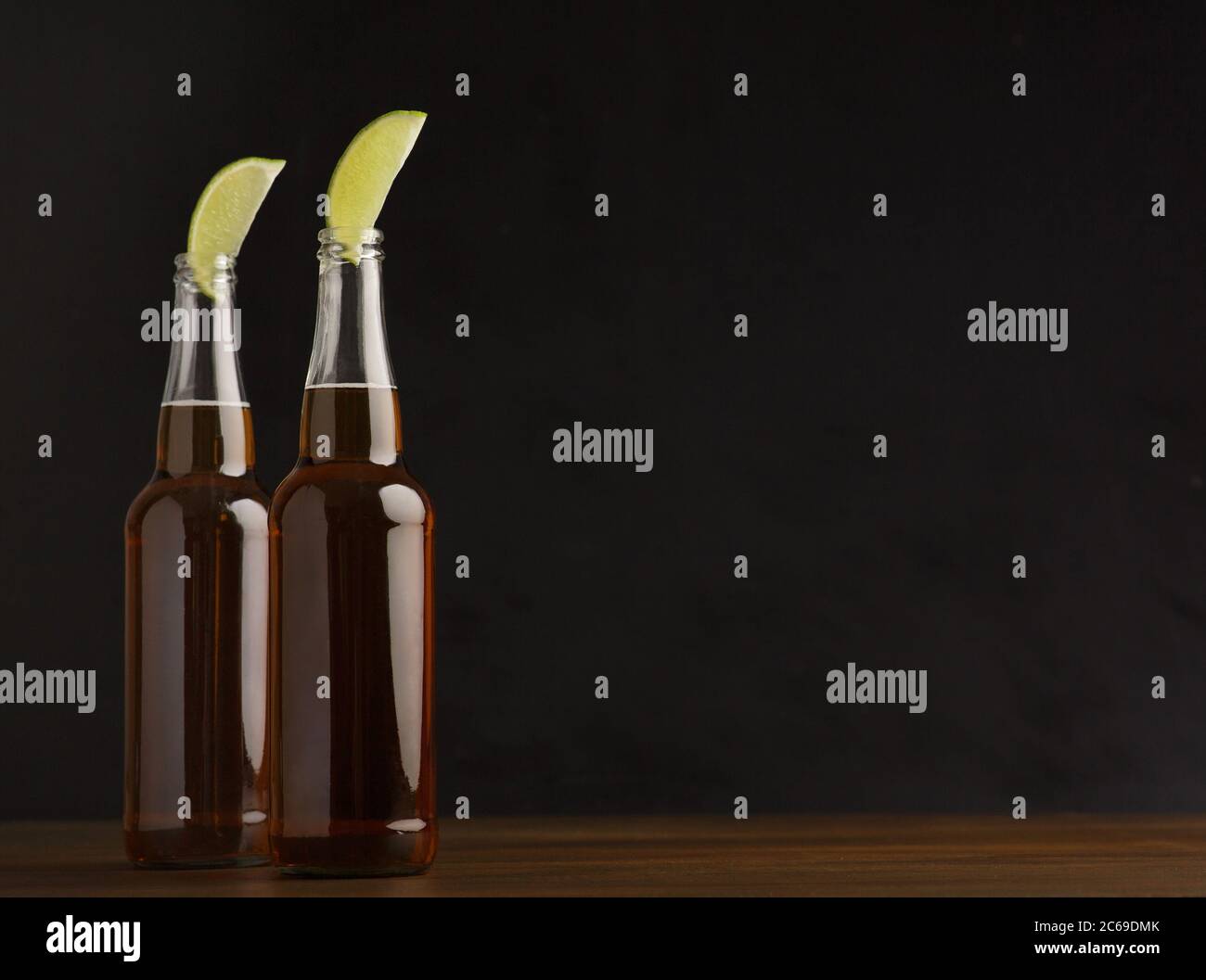 Beer making. Bottles of dark beer with pieces lime on table and black ...