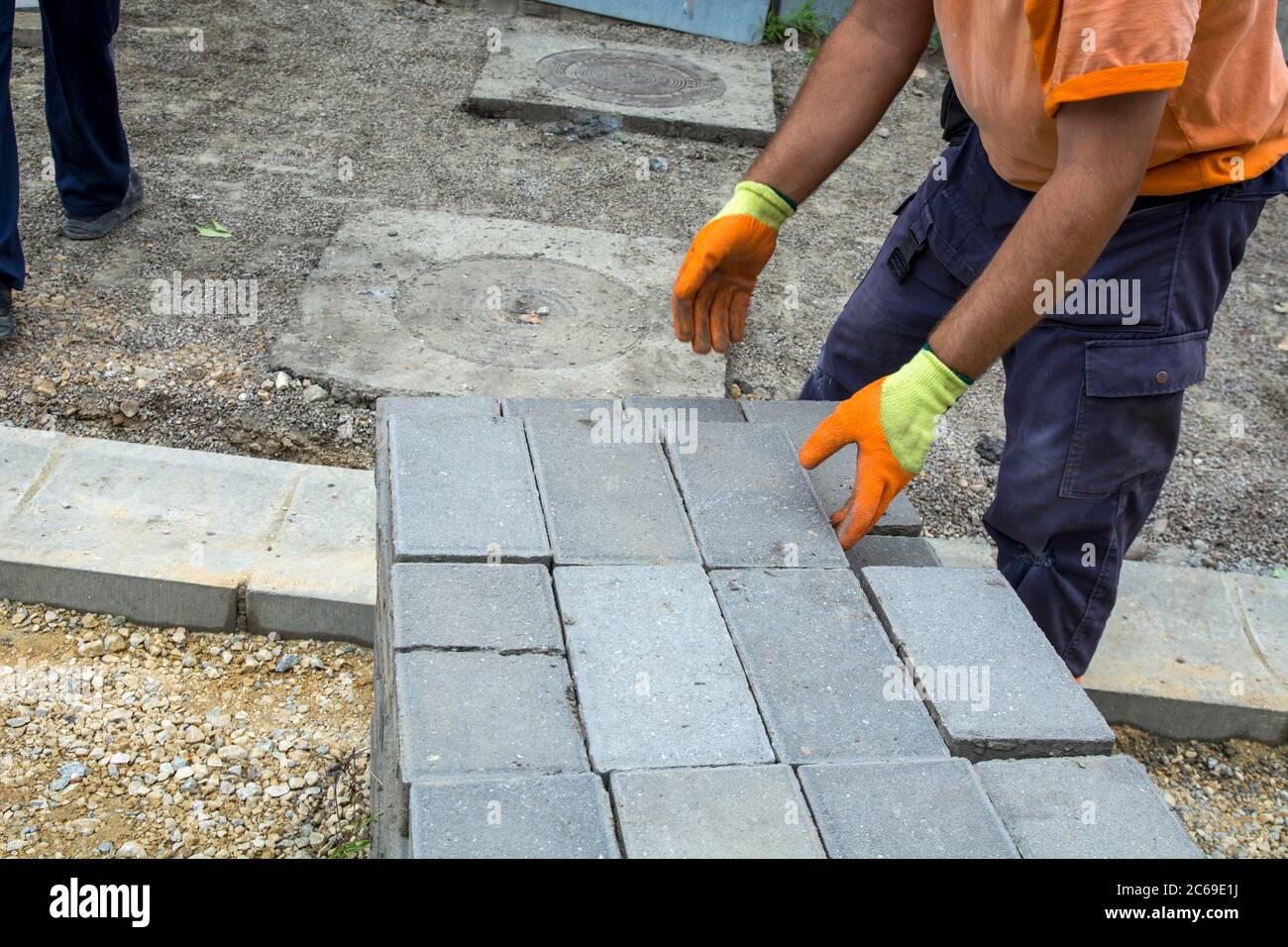 The master is laying new concrete bricks for the sidewalk on the pile ...