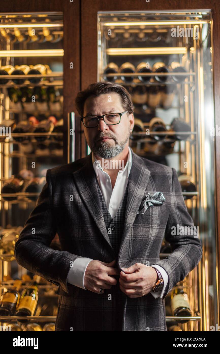 Portrait of a handsome mature male sommelier in tailored suit posing in ...