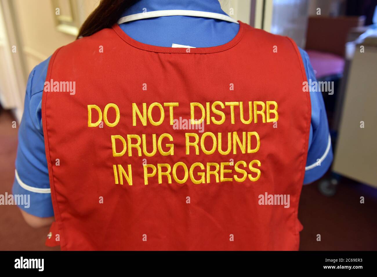 Staff in a care home dispenses drugs wearing a 'Do Not Disturb' tabard ...