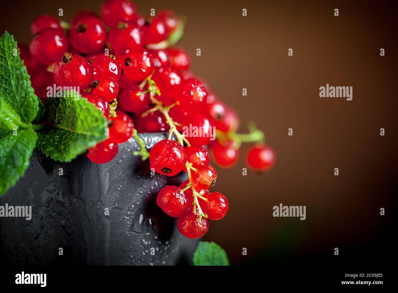 Fresh red currants in a Cup on a dark rustic wooden table. Background ...