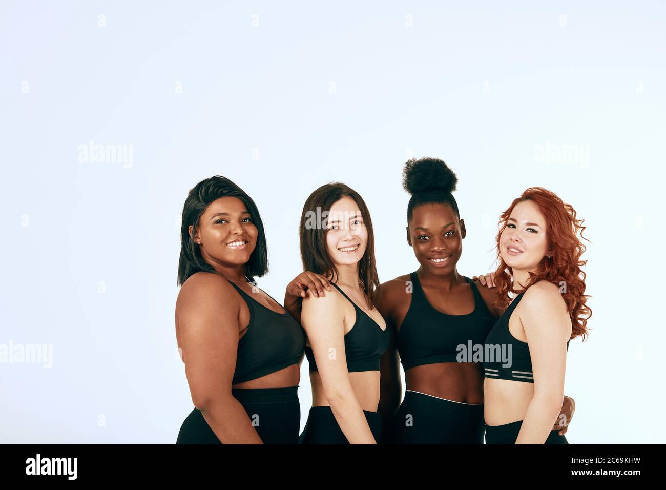 Group of four women of different race, figure type and size in sports ...