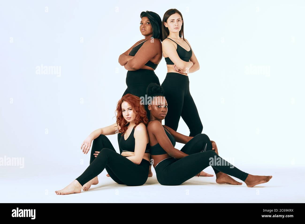 Group of four women of different race, figure type and size in sports ...