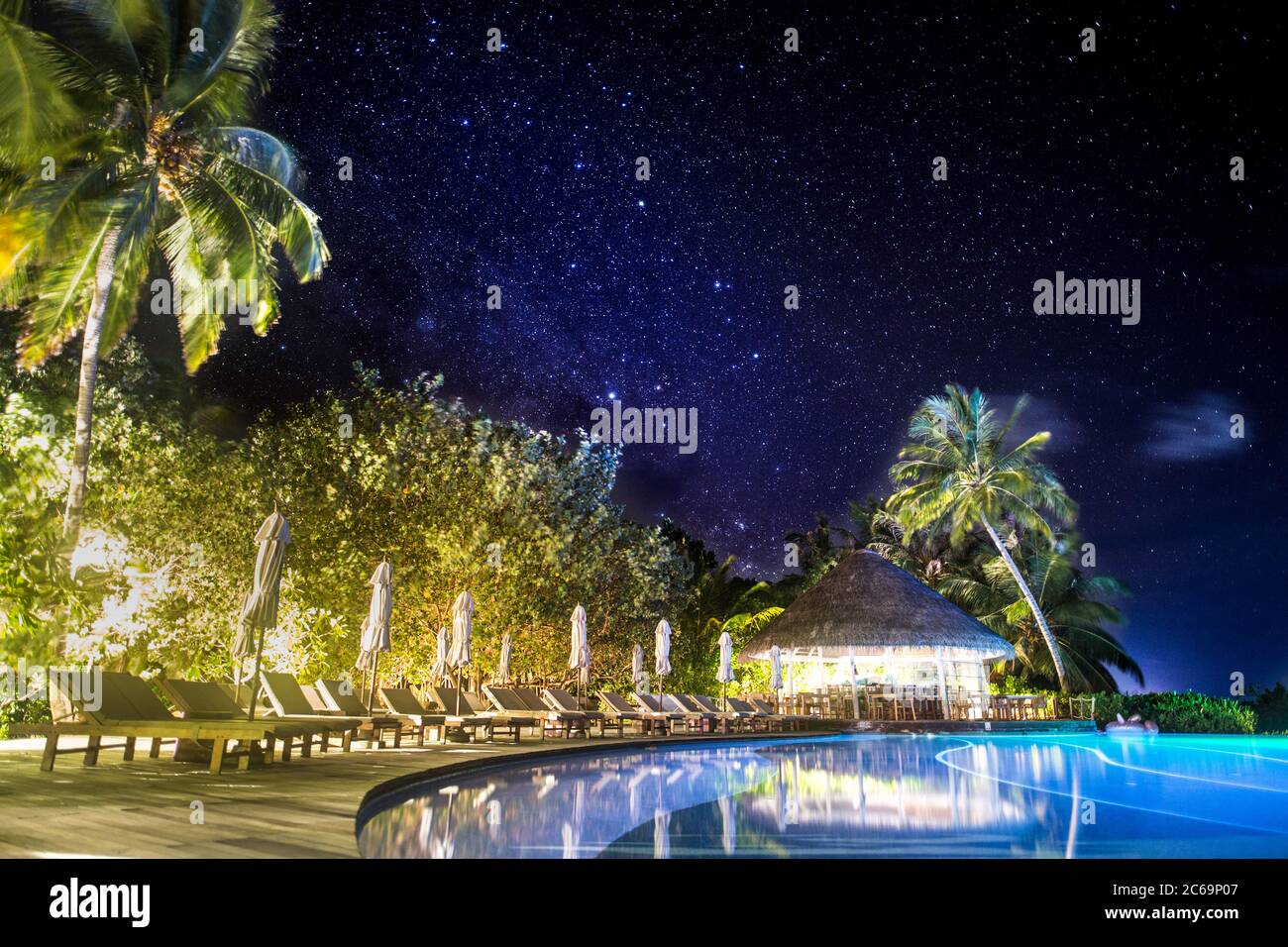 Swimming pool in night illumination under milky way, stars. Palm trees ...