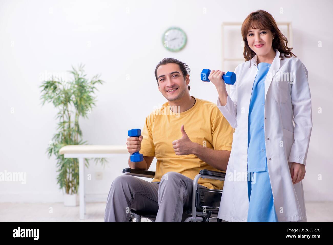 Young male patient in wheel-chair doing physical exercises in hospital ...