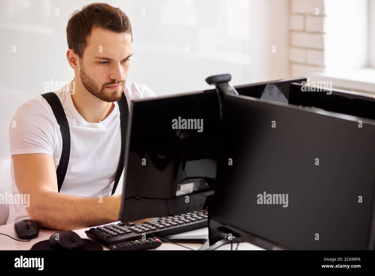 Handsome busy man working on computer, look at screen of computer ...