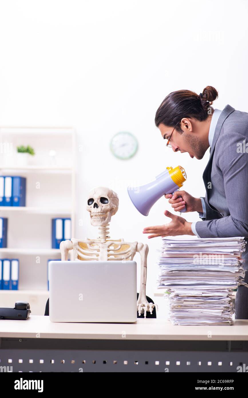 Young employee and skeleton in the office Stock Photo - Alamy