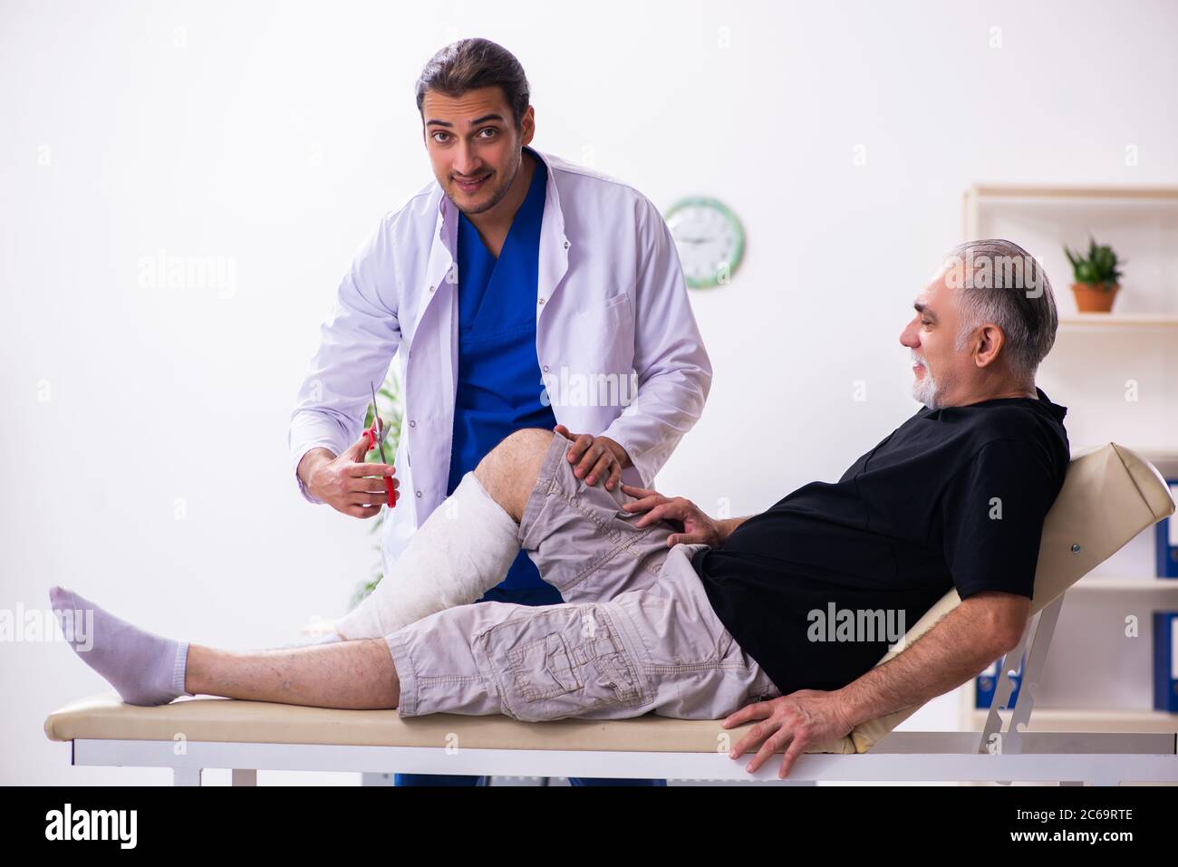 Old injured man visiting young doctor traumatologist Stock Photo - Alamy