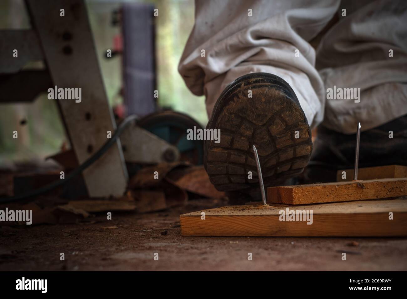 Worker in safety shoes stepping on nails on board wood In the ...